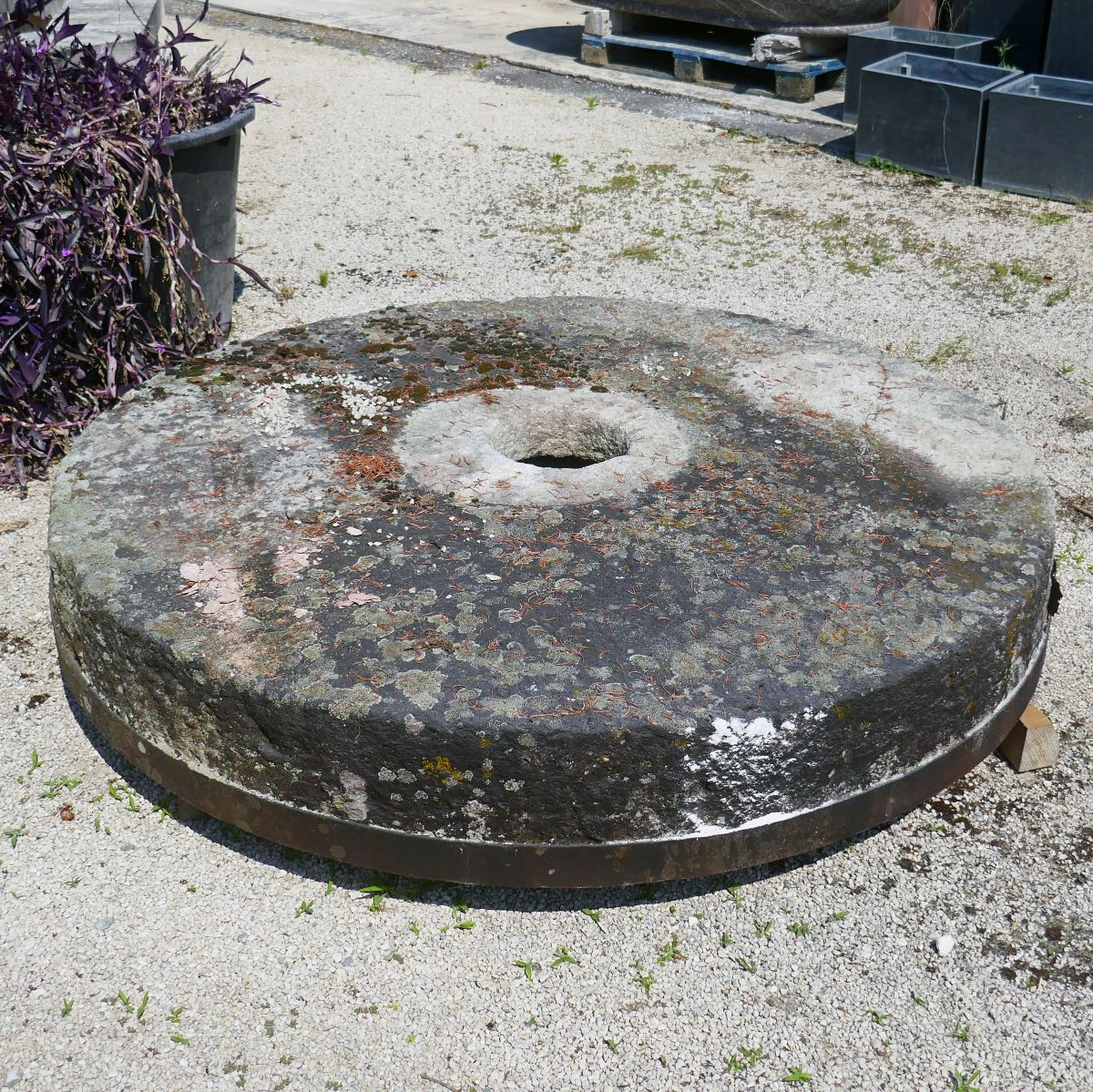 Meule en pierre : ancienne roue de moulin en pierre cerclée de fer