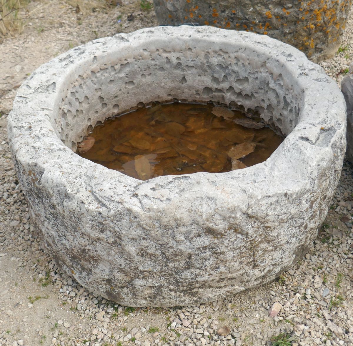 Ancient circular trough in stone as a small flower box or planter
