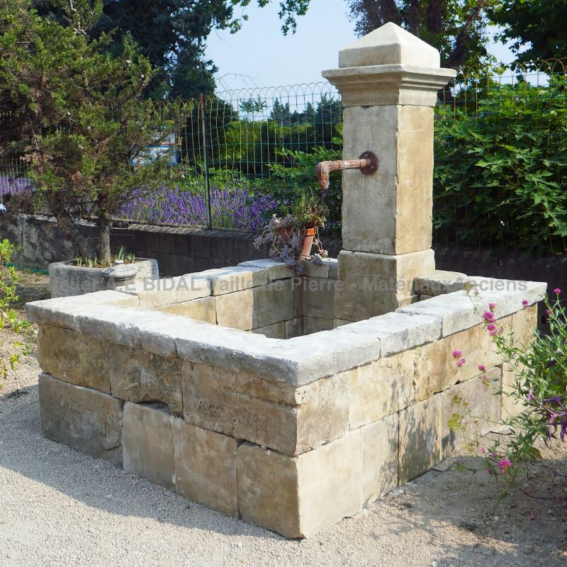 Fontaine avec bassin appareillé de vieilles pierres et étroit fronton