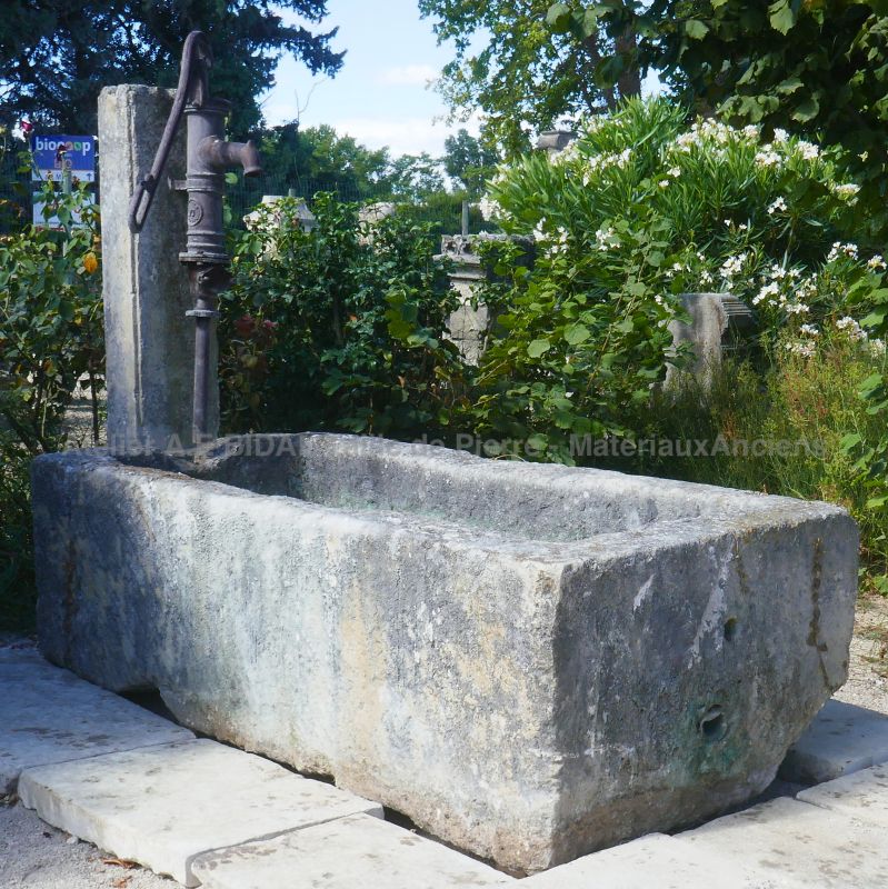 Large fountain in old materials : stone trough and cast-iron hand pump