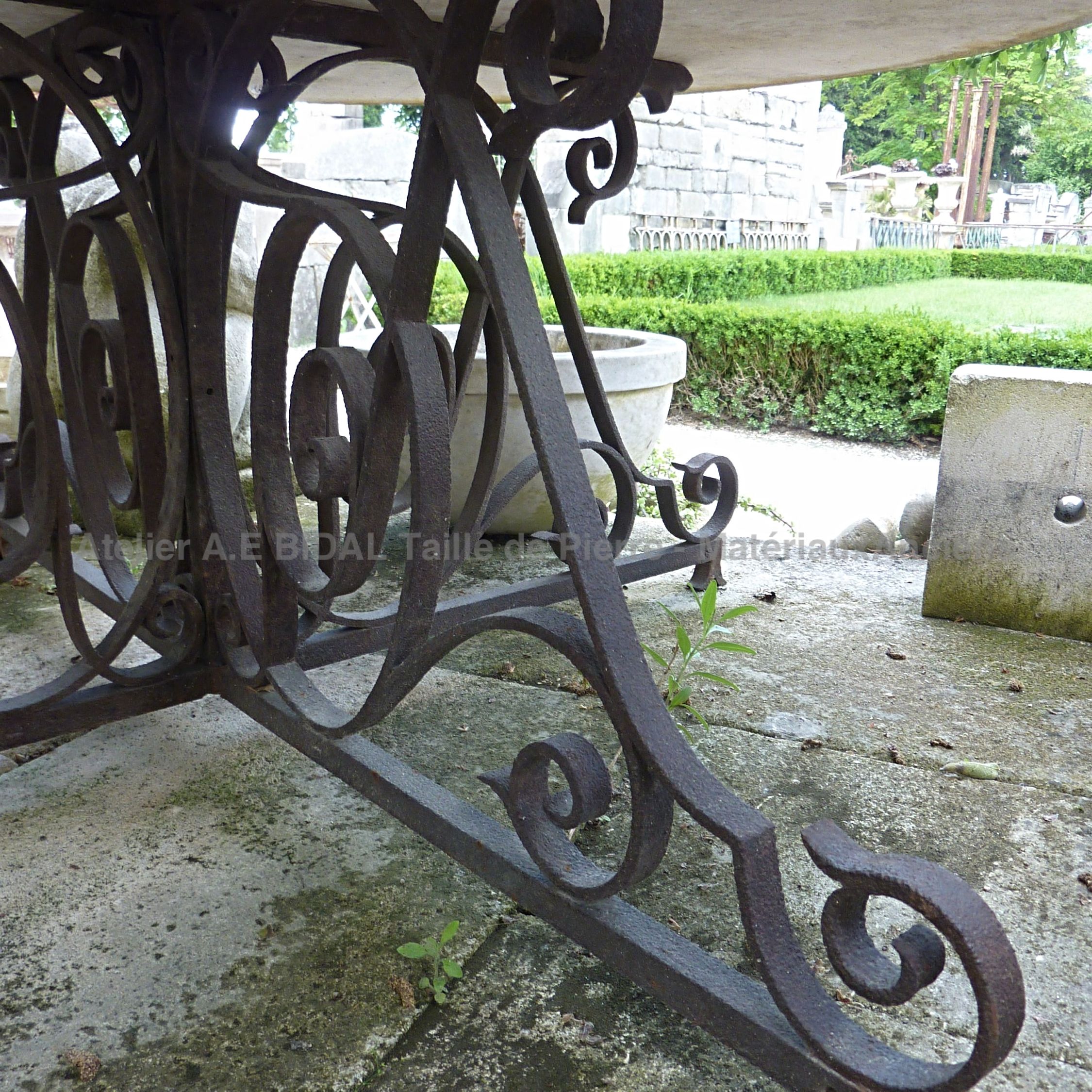 En matériaux anciens- une table basse ancienne en pierre et fer forgé.
