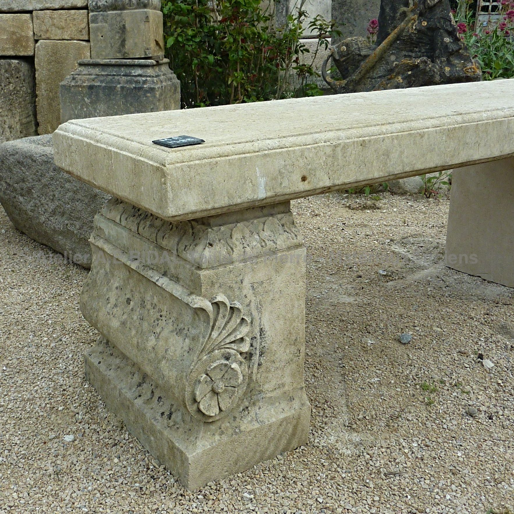 Un banc en pierre aux pieds décorés - beau mobilier de jardin ancien.