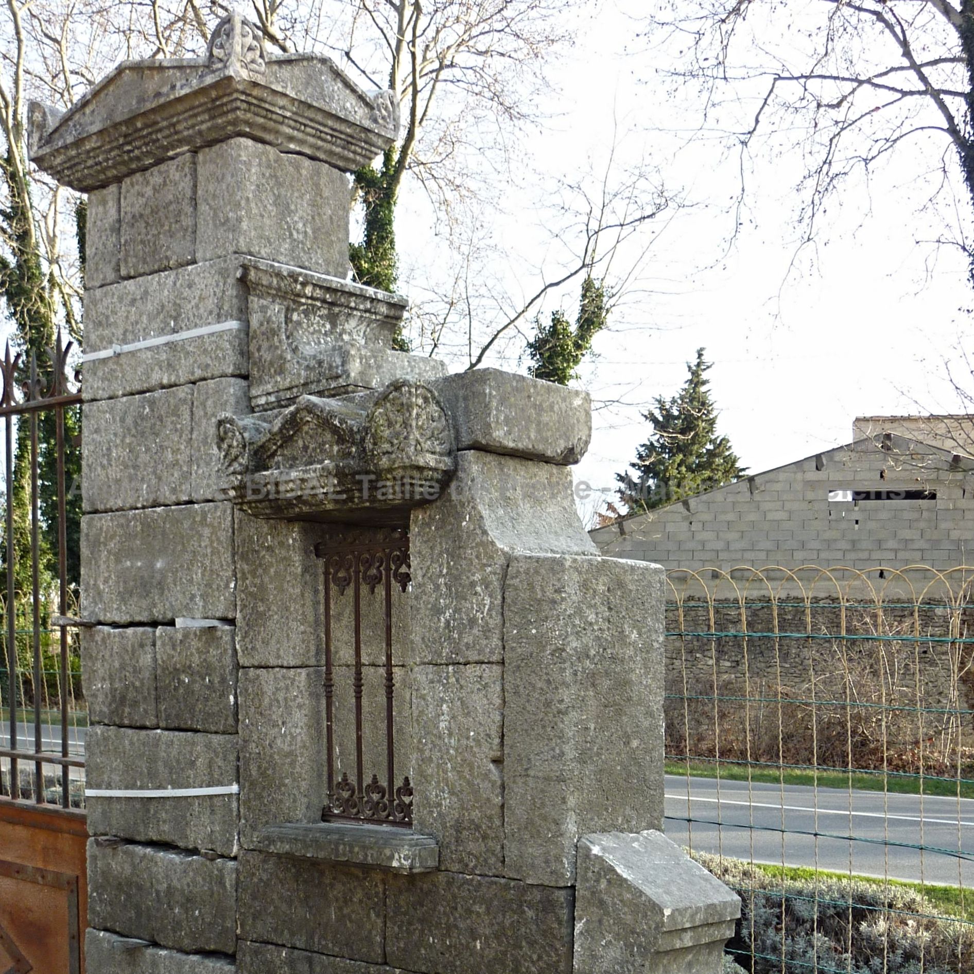 Pair of antique pillars with low stone walls.