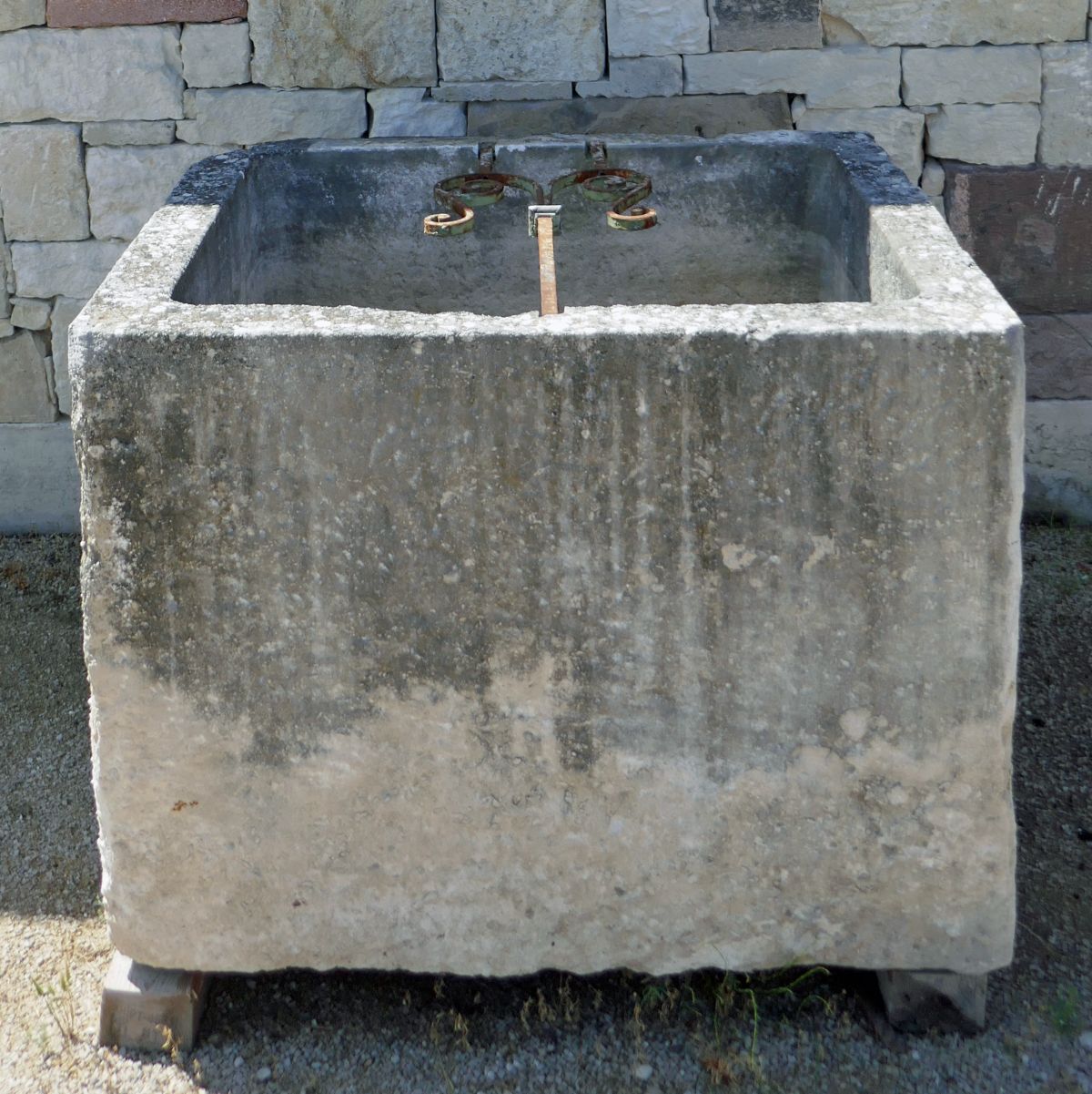 Large antique trough in old stone with metal bucket-rest bars